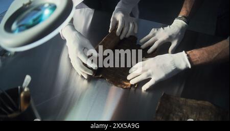 Two archaeologists in gloves carefully roll out ancient Egyptian ...