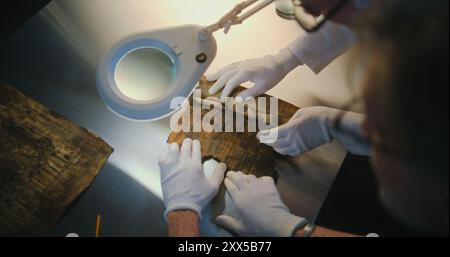 Two archaeologists look through magnifying lamp, study ancient Egyptian ...