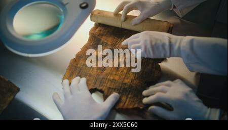Two archaeologists in gloves carefully roll out ancient Egyptian ...