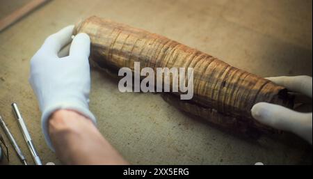 Two archaeologists in gloves carefully roll out ancient Egyptian ...