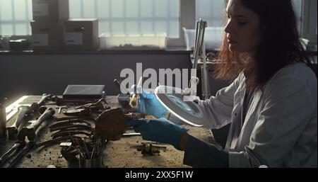 Female paleoanthropologist works with fossil remains in archaeological ...