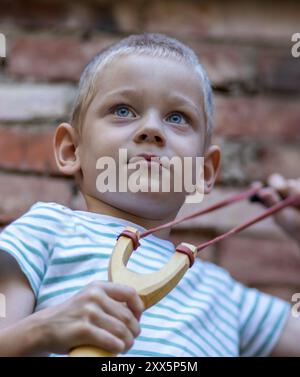A little boy is playing with a slingshot on the street Stock Photo - Alamy