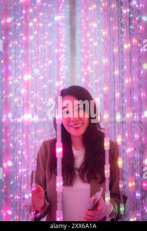 A woman poses surrounded by colorful LED lights in an immersive digital ...