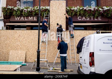 Workmen attach boards to the Walmer Castle pub as preparations continue ...