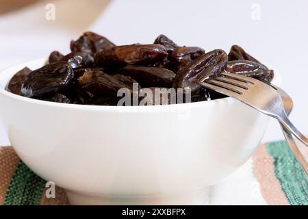A portion of dates inside a white ceramic bowl photographed up close ...