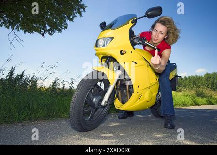 Young woman on a motorbike gives the finger Stock Photo - Alamy