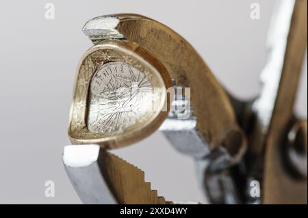 A bent euro between the jaws of a pair of pliers with a concave bend ...