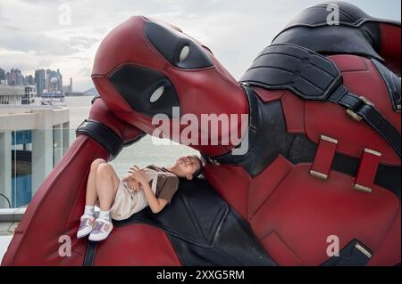 A child poses for a photo with the 8-meter installation of Marvel's ...