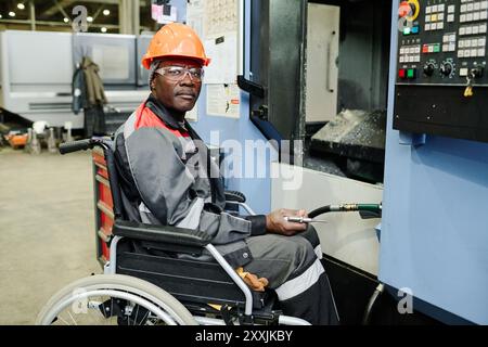 Industrial worker in wheelchair operating complex machinery in ...