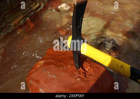 A pickaxe stuck into a piece of juicy red clay lying in a stream, raw ...