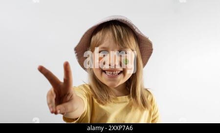 Little girl with emojis on face showing v gesture portrait Stock Photo ...
