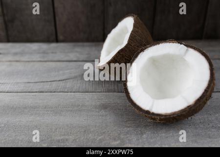 Broken coconuts on gray wooden background with palm leaf. White coconut ...