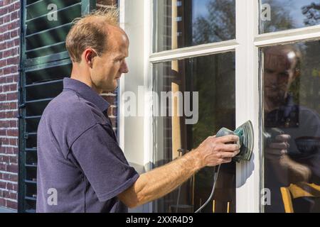 Caucasian painter sanding window frame with electric sander Stock Photo ...