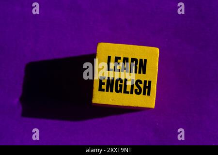 Learn english message written on ripped yellow paper with blue background. Conceptual learn ...