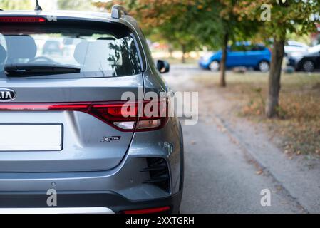 Rear view of a parked grey Kia SUV on a quiet suburban street ...