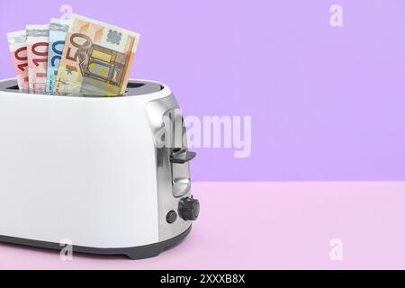 Toaster with euro banknotes on table near lilac wall Stock Photo - Alamy