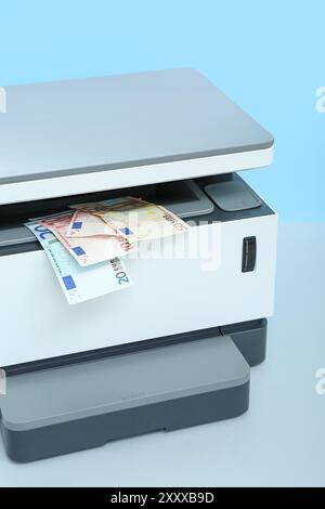Laser printer with euro banknotes on table near blue wall Stock Photo ...