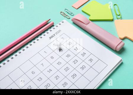 Calendar with office stationery on turquoise background Stock Photo - Alamy