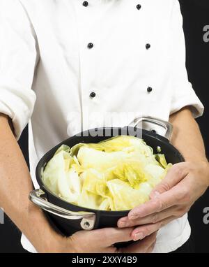 Chef in white jacket holding around a casserole of boiled cabbage Stock ...