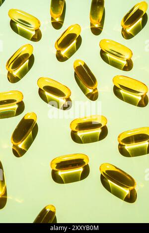 Yellow translucent vitamin capsules arranged on green background and ...