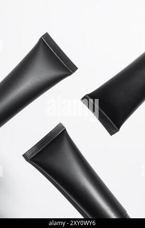 Elegant black cosmetic tubes with a matte finish, presented on a clean ...