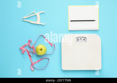 Flat lay composition with body fat caliper, measuring tape and notebook ...