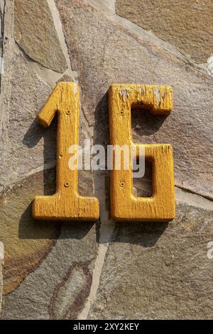 Yellow number sixteen on a stone wall Stock Photo - Alamy
