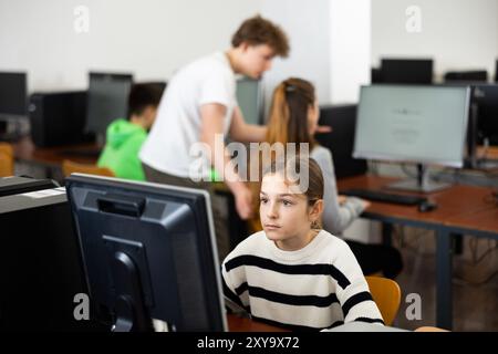Teen schoolgirl learning basics of programming in computer college ...