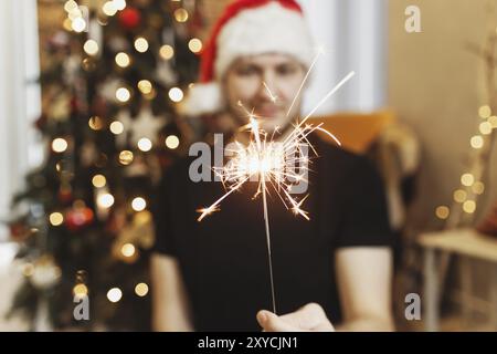 Man holds burning sparkler in dark room against backdrop of New Happy ...
