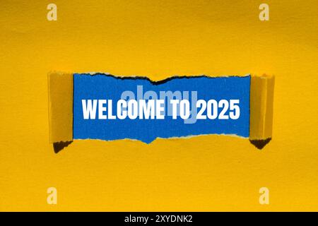 Welcome 2025 message written on ripped torn paper piece with brown background. Conceptual ...