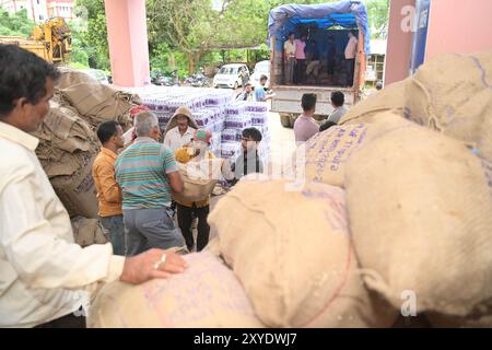 Laborers are carrying packets of food and stacking them in a truck as ...