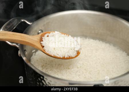 Taking boiled rice from pot with spoon, closeup Stock Photo - Alamy