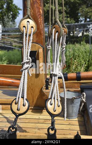 A close-up of ropes and pulleys on a traditional sailboat in grayscale ...