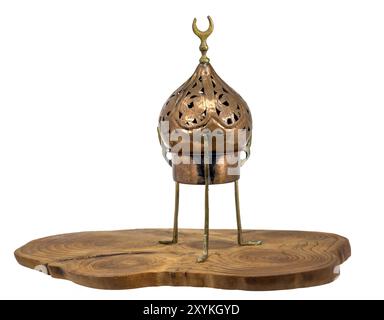 Old oriental incense burner made of copper stands on a wooden disc ...