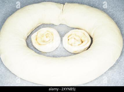 Closeup of raw cinnamon roll and cinnamon buns on baking paper Stock ...