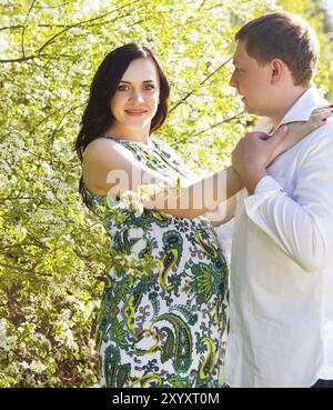 Young happy pregnant couple in cocktail clothes looking at each other ...