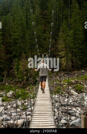 A man walks on a suspension bridge over the river Stock Photo - Alamy