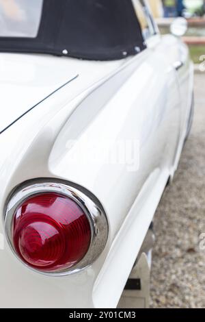 A vintage car tail light illuminates a cobbled street, embodying ...