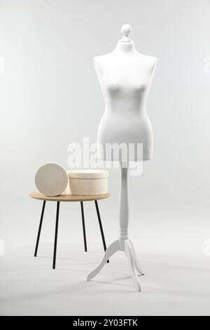 Mannequin and boxes on side table against light grey background ...