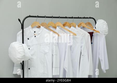 Chefs' uniforms on clothing rack against grey background Stock Photo ...