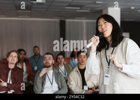 Asian businesswoman giving speech, holding microphone and smiling ...