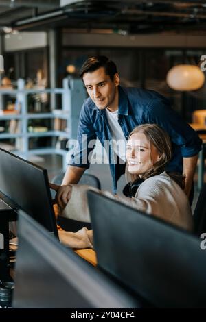 Female computer programmer pointing at desktop screen while discussing ...