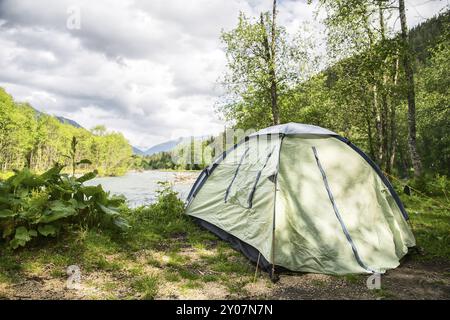 Tourist tent on the high bank of the river at sunset. Beautiful summer ...