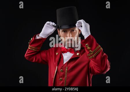 Portrait of showman in red costume, cane and hat on black background ...