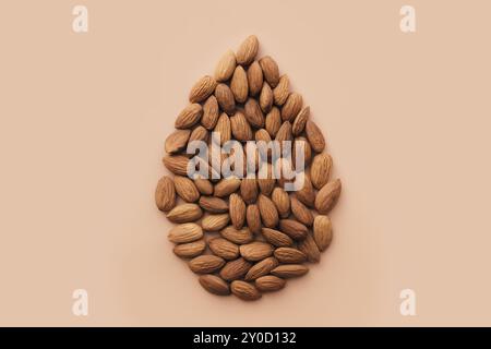 Raw almond kernels drop shape on beige background. Cosmetic and healthy ...