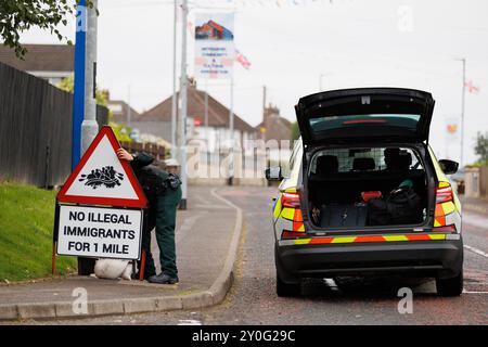 PSNI officer removing a road sign with image of people a dingy boat ...