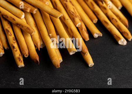 Thin and long bread sticks made of wheat flour and a glass of milk ...
