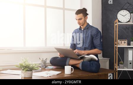 Flexible man practicing yoga at workplace Stock Photo - Alamy