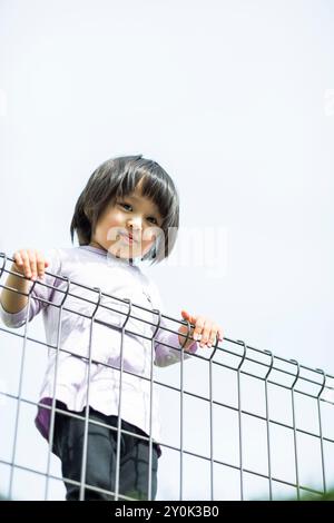 Girl leaning forward from the fence Stock Photo - Alamy