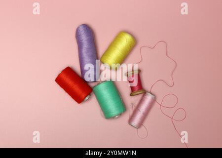 Spools of thread and needles on a pink background with space for text ...